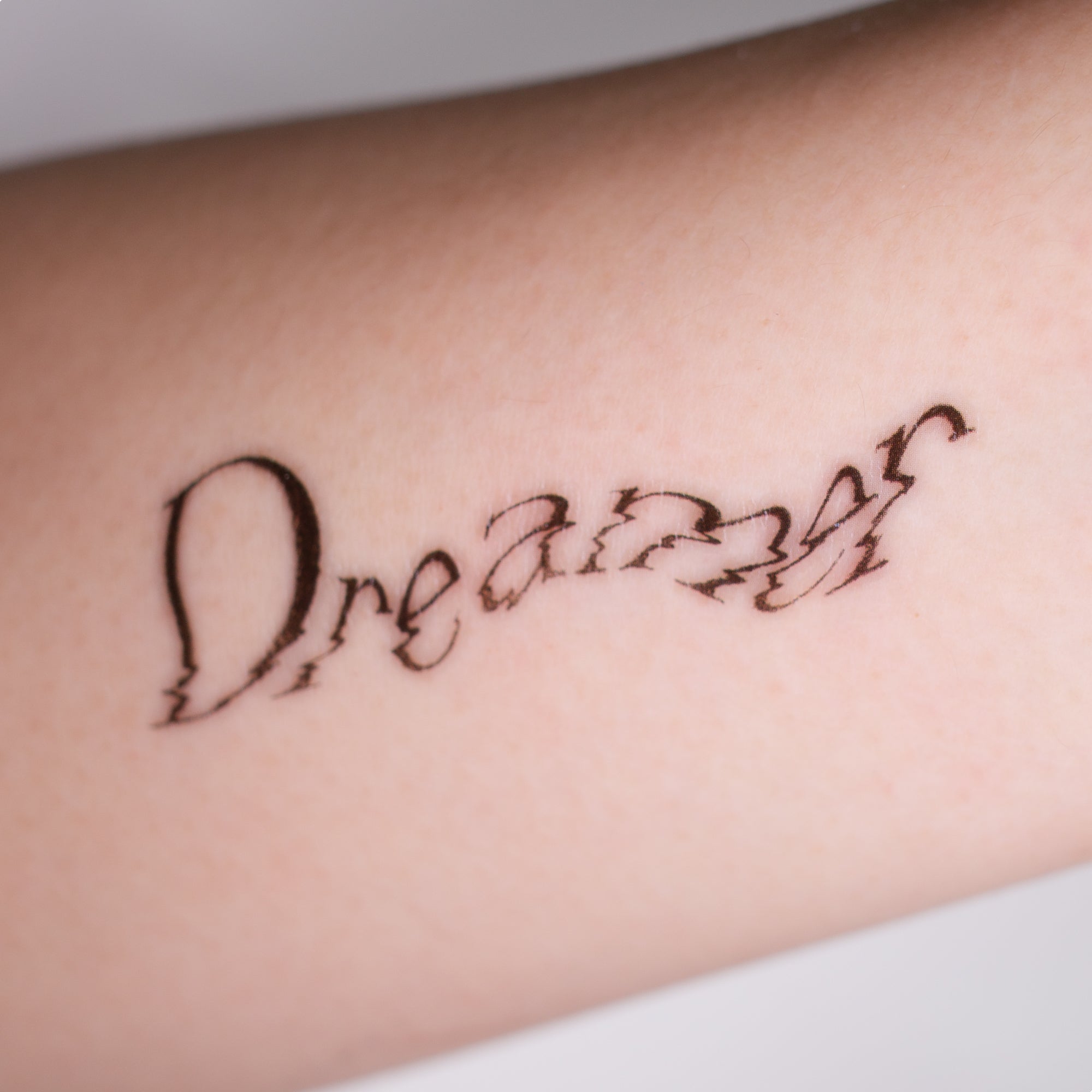 The Word Dream In Cursive Tattoo